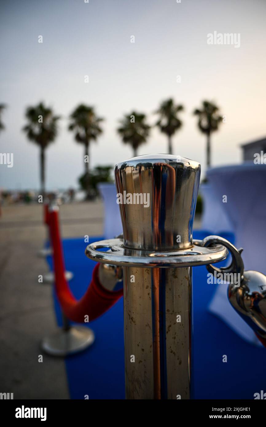 Vip area is set up outside for an event with white cocktail tables, red ...