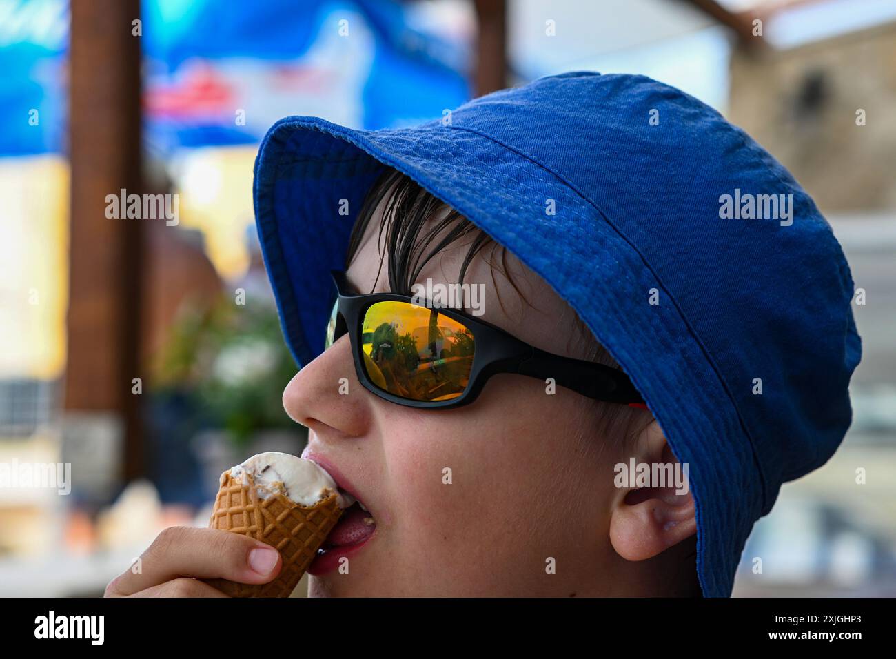 Young boy is happily enjoying an ice cream cone outdoors on a summer ...