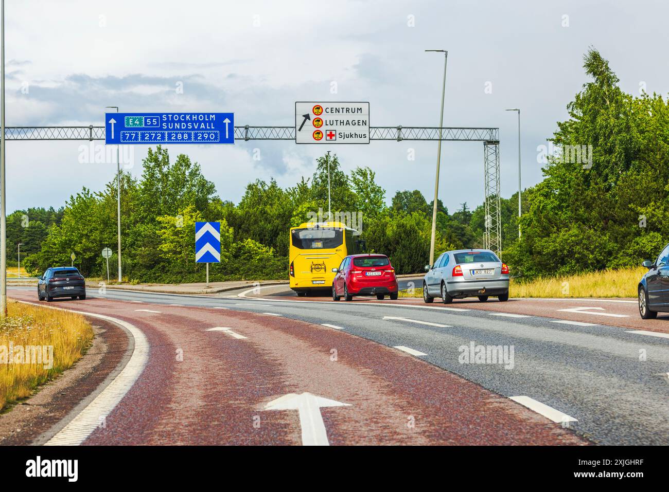 Highway junction with overhead road signs, cars and bus driving on ...