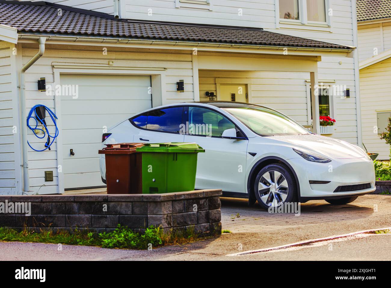 View of white electric car parked in front of modern white house with ...