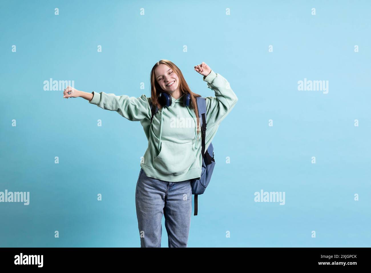 Jolly young girl doing happy dance, feeling joyful, isolated over blue ...