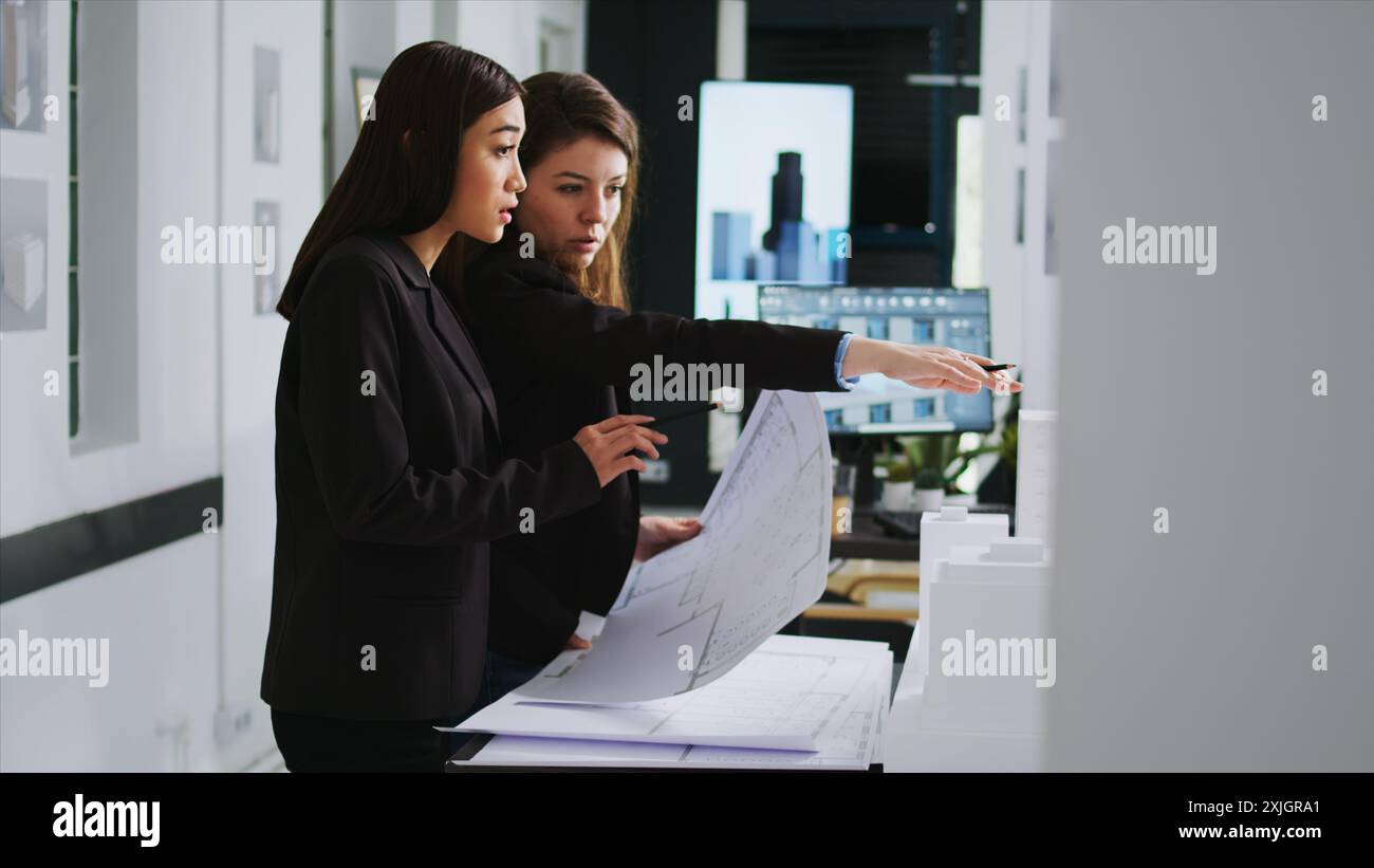 Startup team working with architectural blueprint plans, studying scale ...