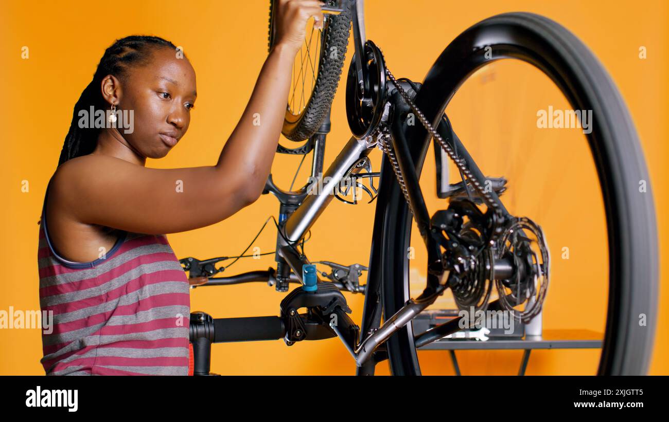 African american woman checking bicycle performance by spinning pedals ...