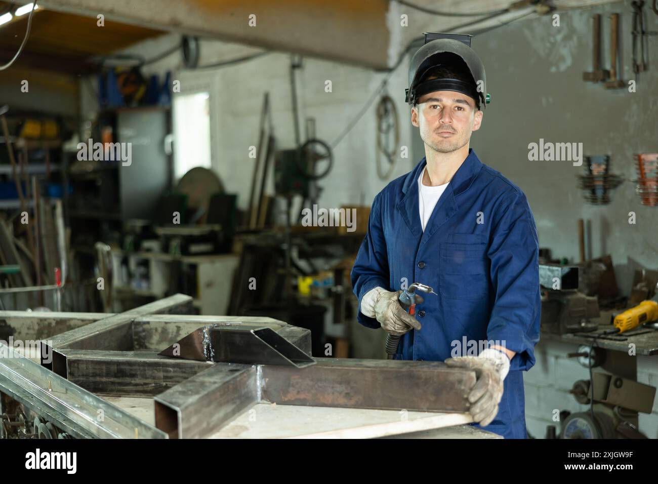 Male welder standing with a welding semi-automatic machine and a safety ...