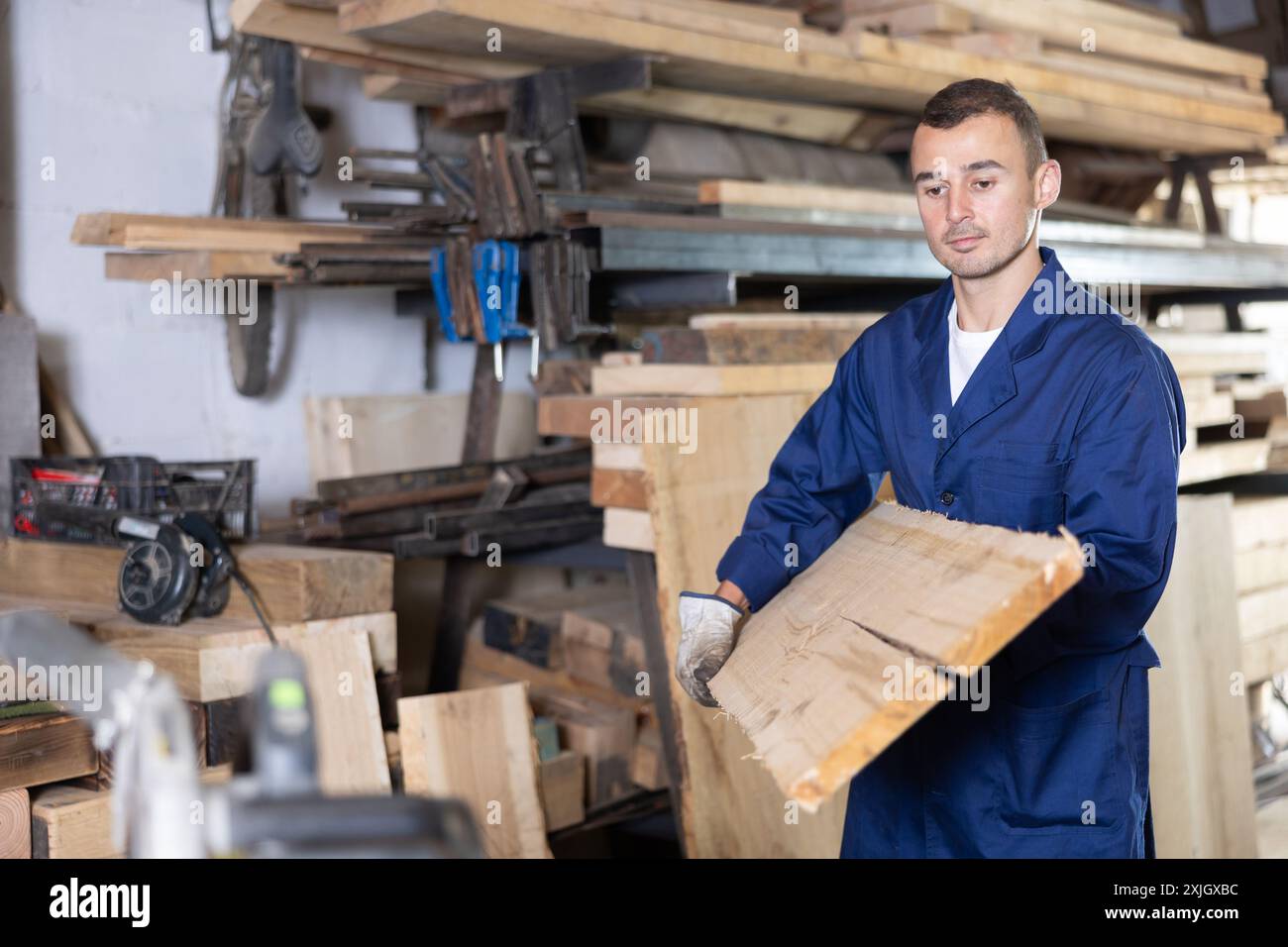 Male sawmill worker stores wooden boards in enterprise warehouse Stock ...