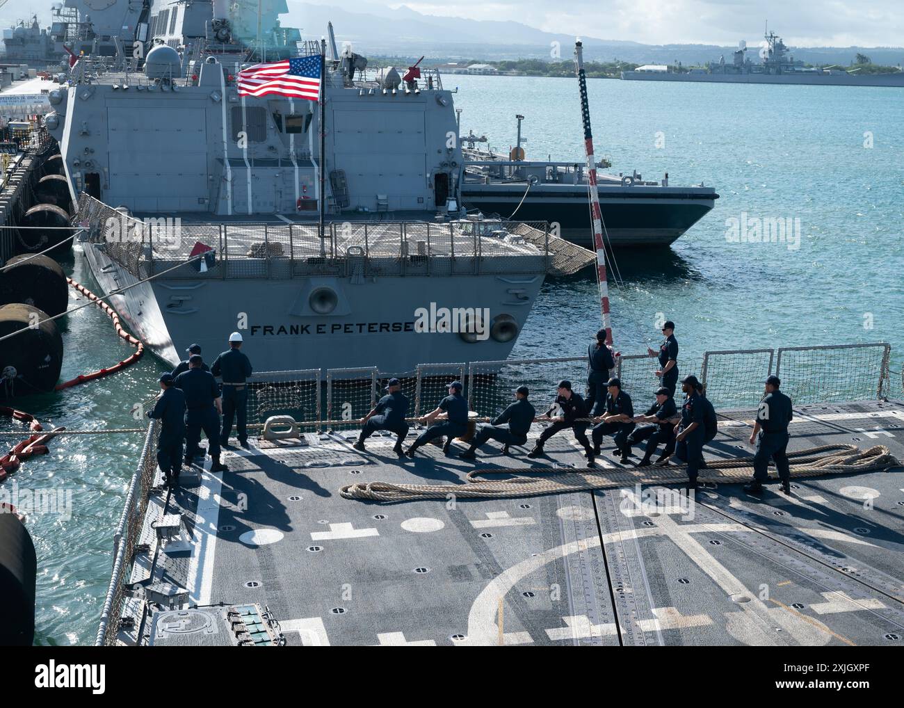 Sailors heave around on a mooring line during a sea-and-anchor evolution while getting underway ...