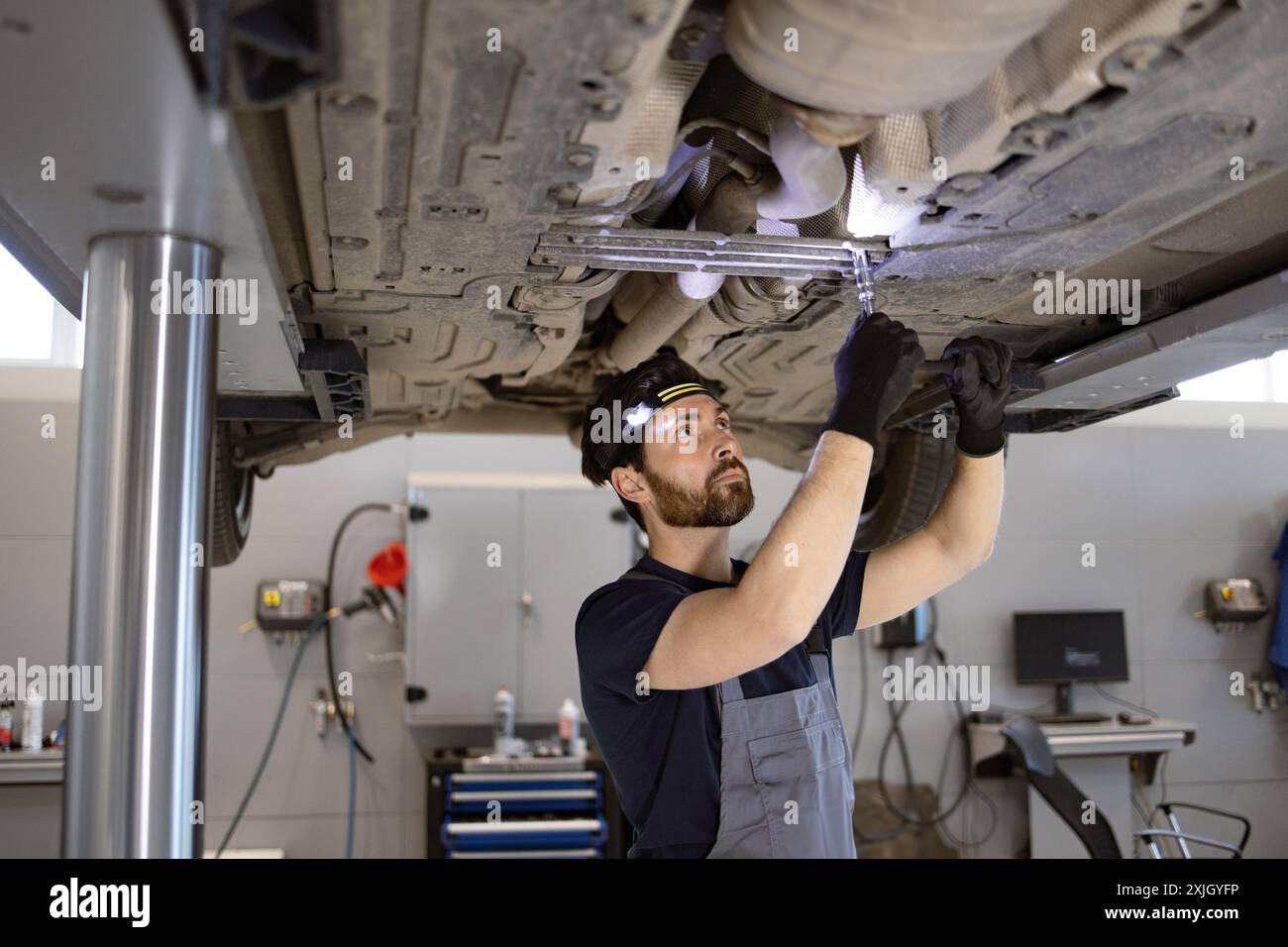 Mechanic working under car in auto repair shop Stock Photo - Alamy