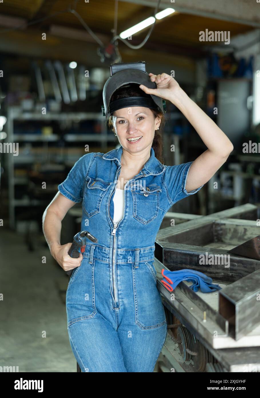 Portrait of a female welder standing with a welding semi-automatic ...