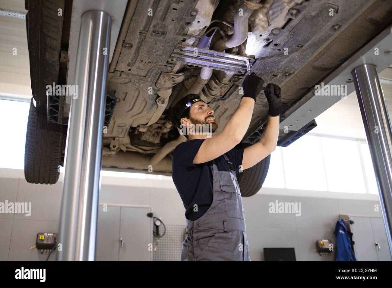 Auto mechanic working under car in service garage Stock Photo - Alamy