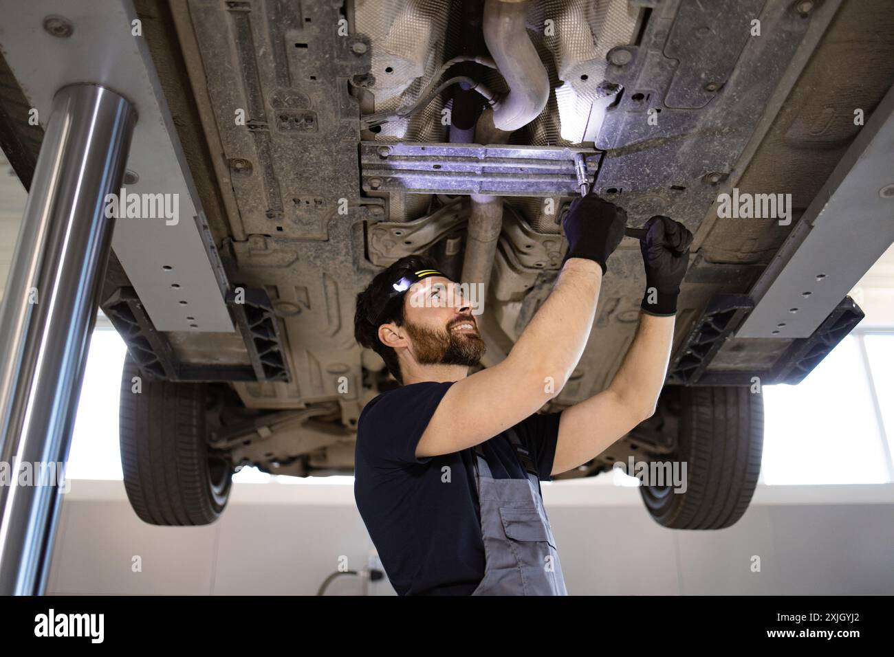 Mechanic working underneath car on lift in auto repair shop Stock Photo ...