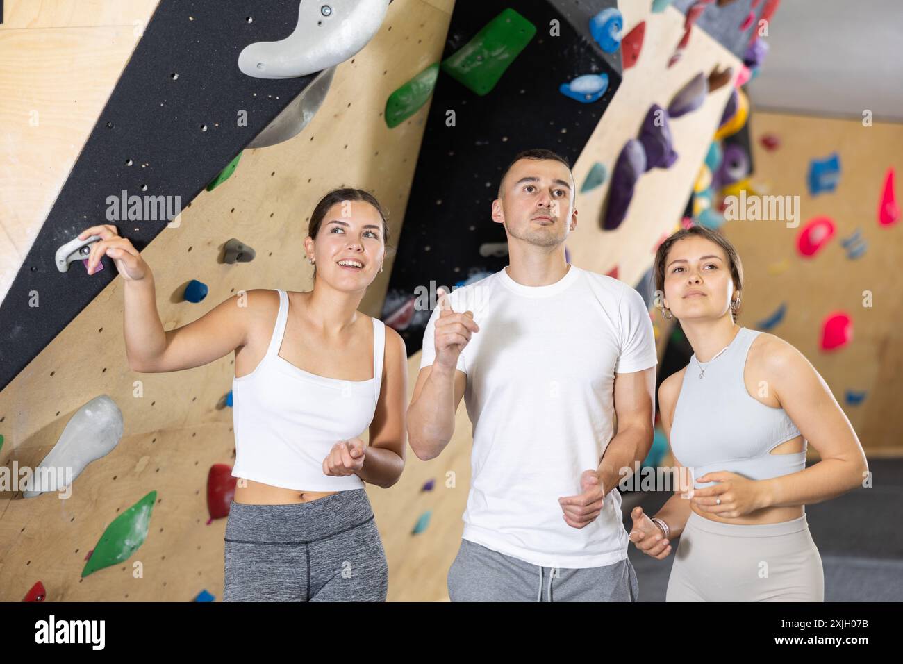Group of friends planning climbing strategy at indoor bouldering gym ...