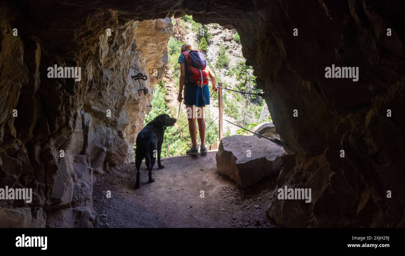 Single adult woman and her black lab hike through a tunnel along the ...