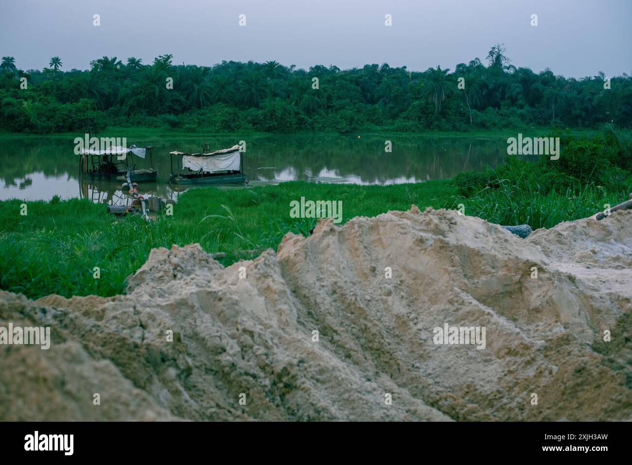 A sand quarry site in the background thick green forest with blue sky ...