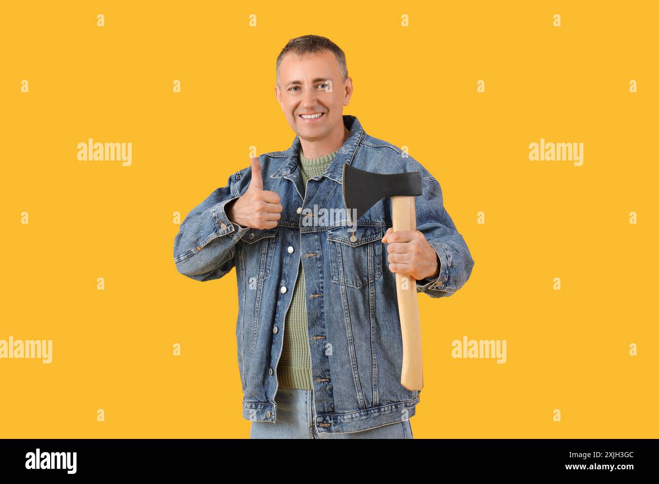 Portrait of adult lumberjack with axe showing thumb-up on orange ...