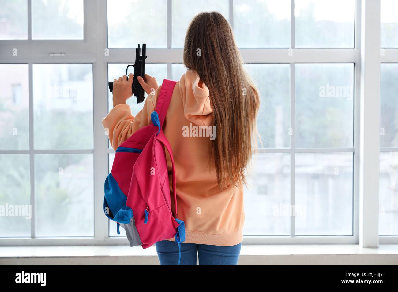 Female student with gun at school, back view Stock Photo - Alamy