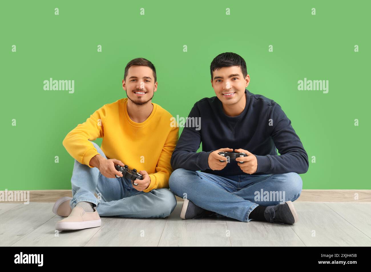 Young brothers playing video games on green background Stock Photo - Alamy