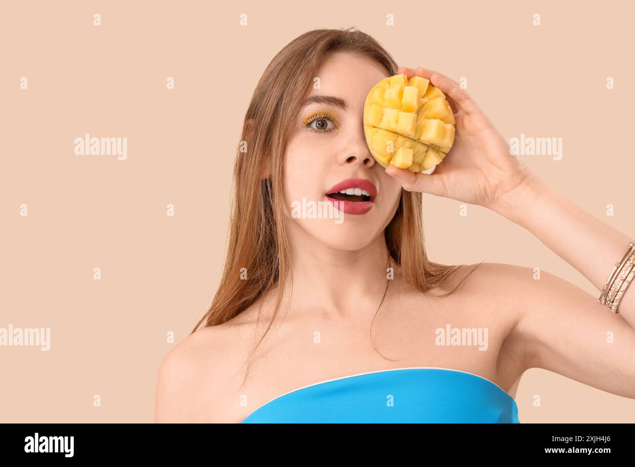 Beautiful young woman with cut sweet mango fruit on beige background ...