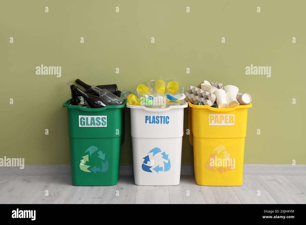 Full trash bins with different types of garbage near green wall ...