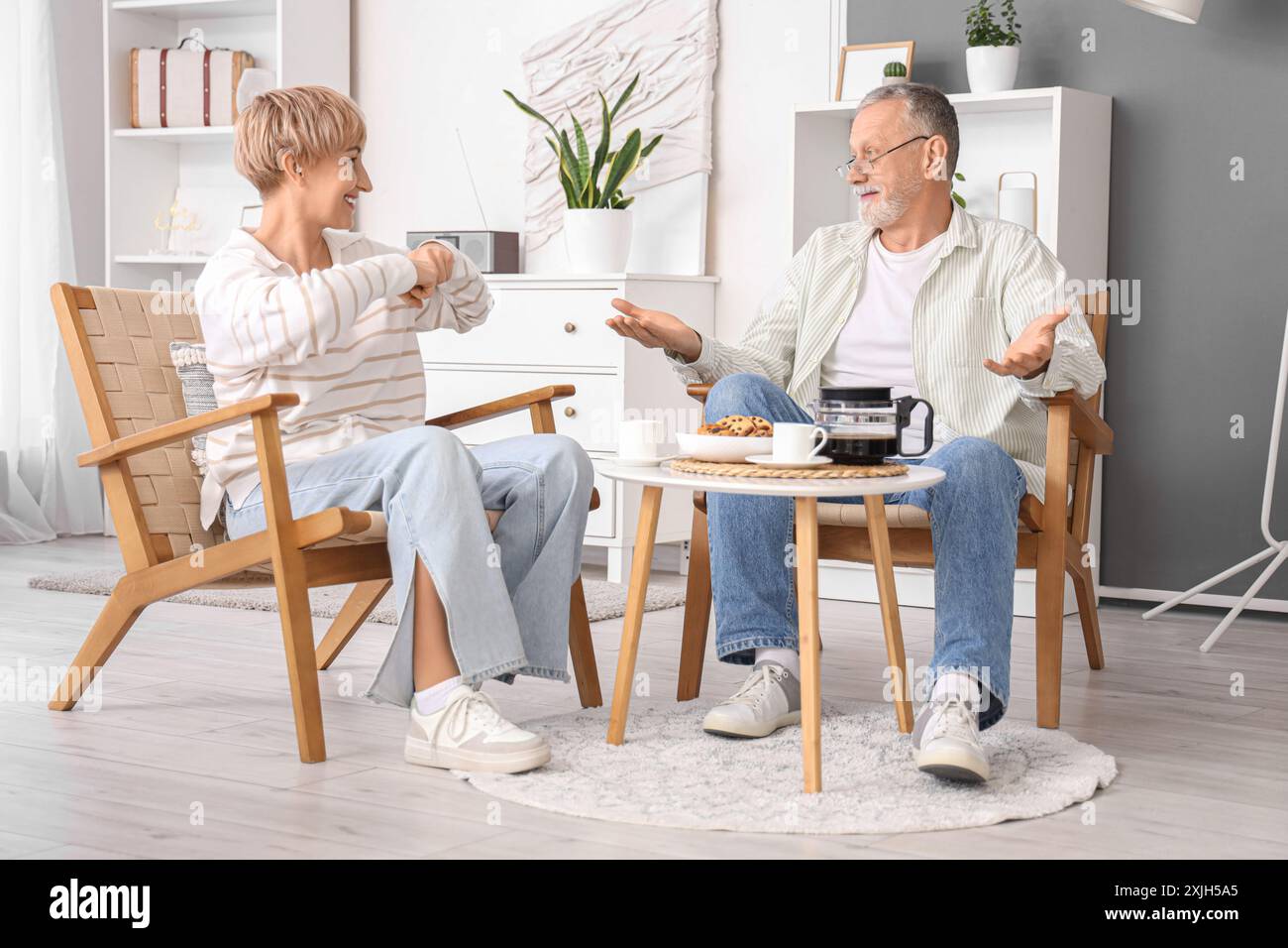 Mature deaf mute couple using sign language in chairs at home Stock ...