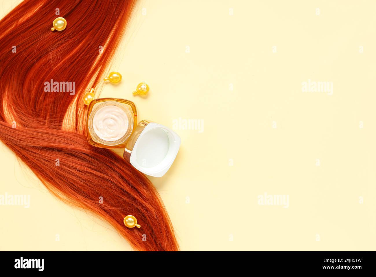 Red strand with jar of hair mask and capsules on yellow background ...
