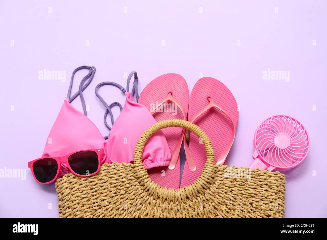 Straw bag with flip flops, swimsuit, sunglasses and portable electric ...