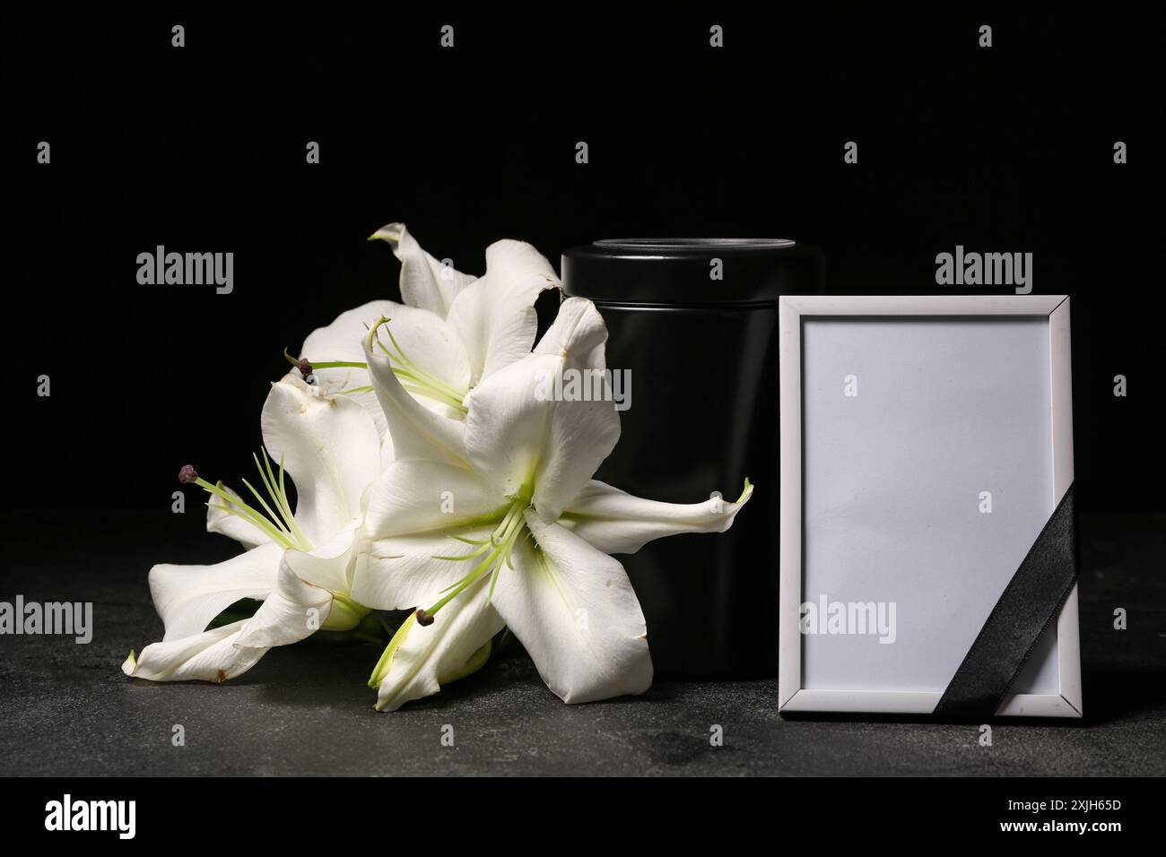 Blank funeral photo frame, mortuary urn and flowers on black background ...