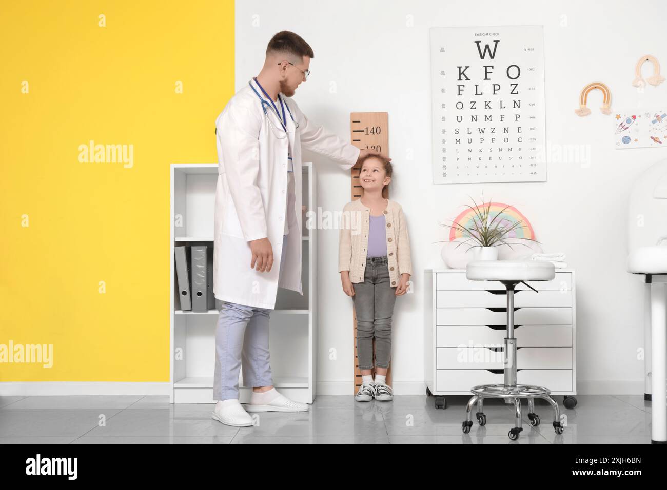 Male pediatrician measuring little girl's height in clinic Stock Photo ...