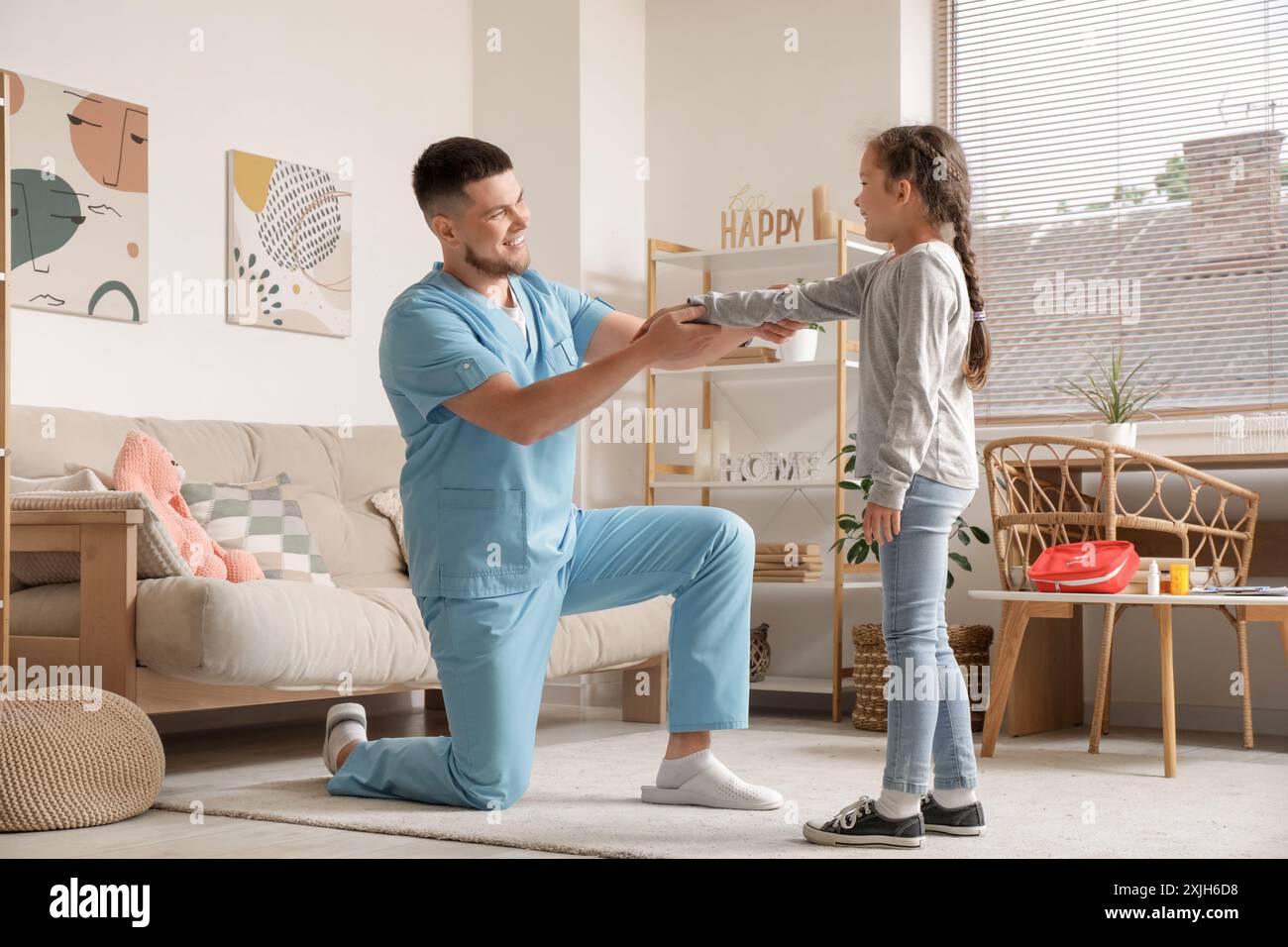 Male pediatrician examining little girl's arm at home Stock Photo - Alamy