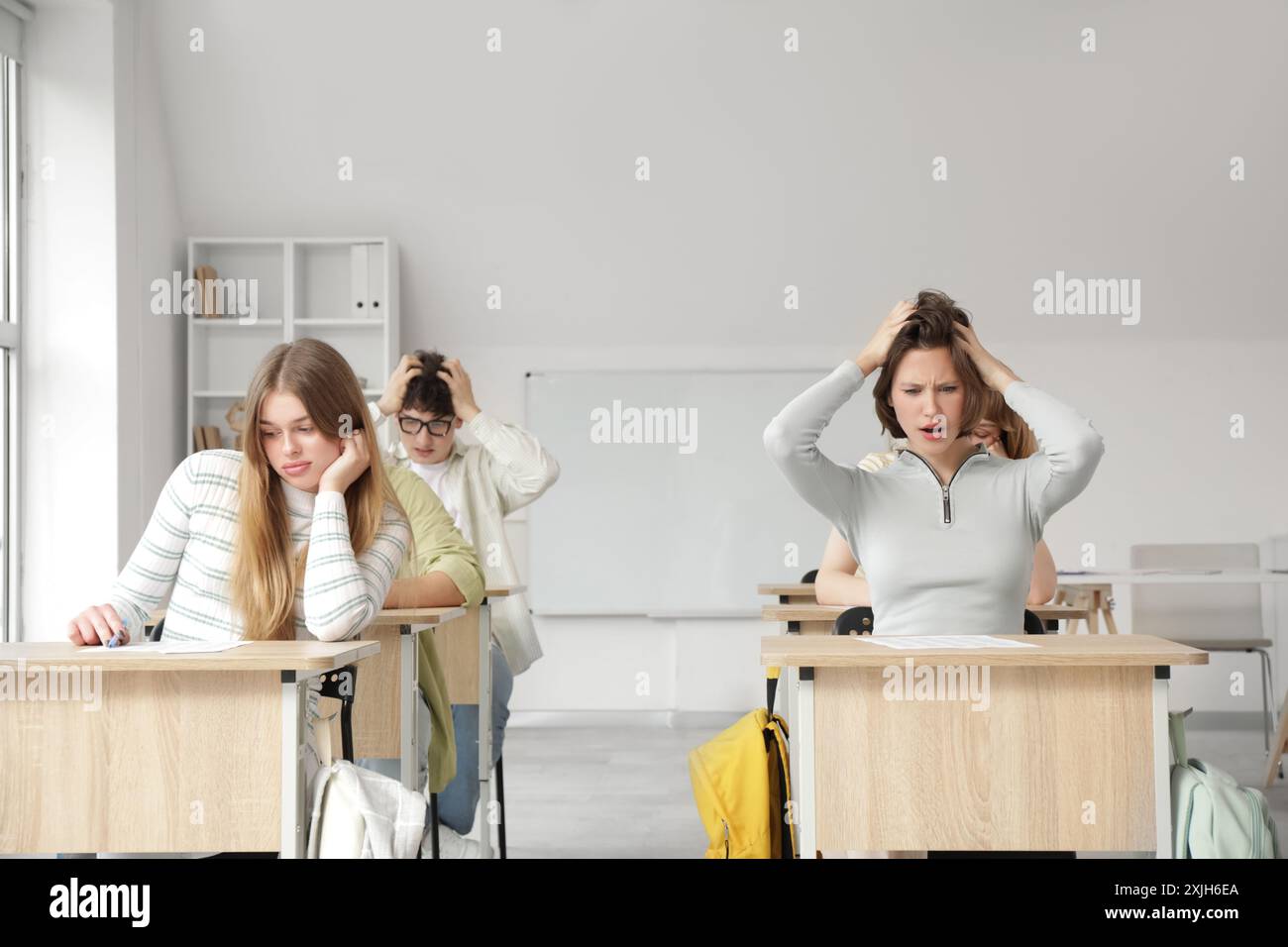Stressed students passing exam at desks in classroom Stock Photo - Alamy