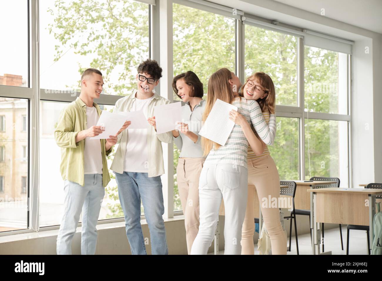 Happy students after passing exam in classroom Stock Photo - Alamy