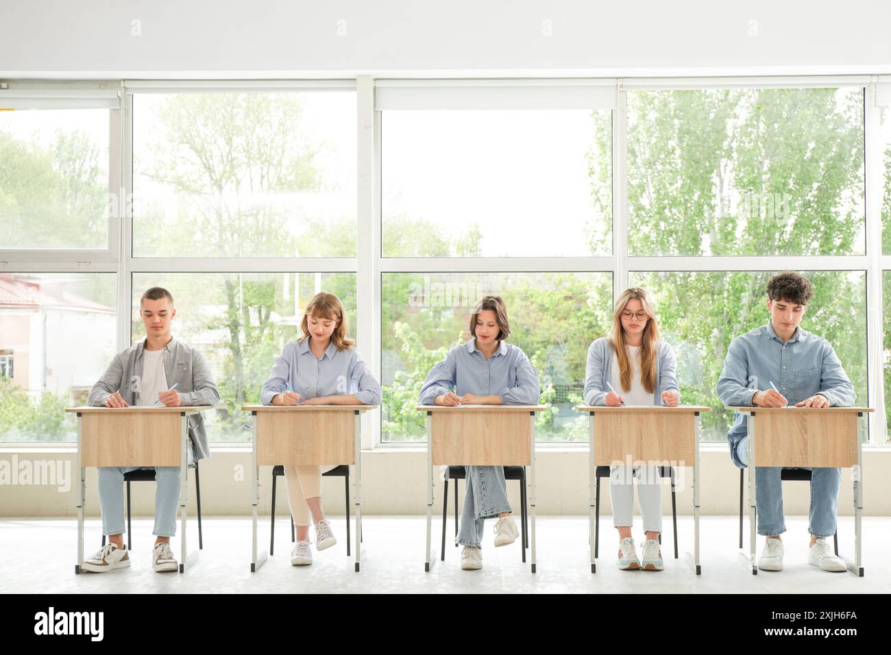 Group of students passing exam in classroom Stock Photo - Alamy
