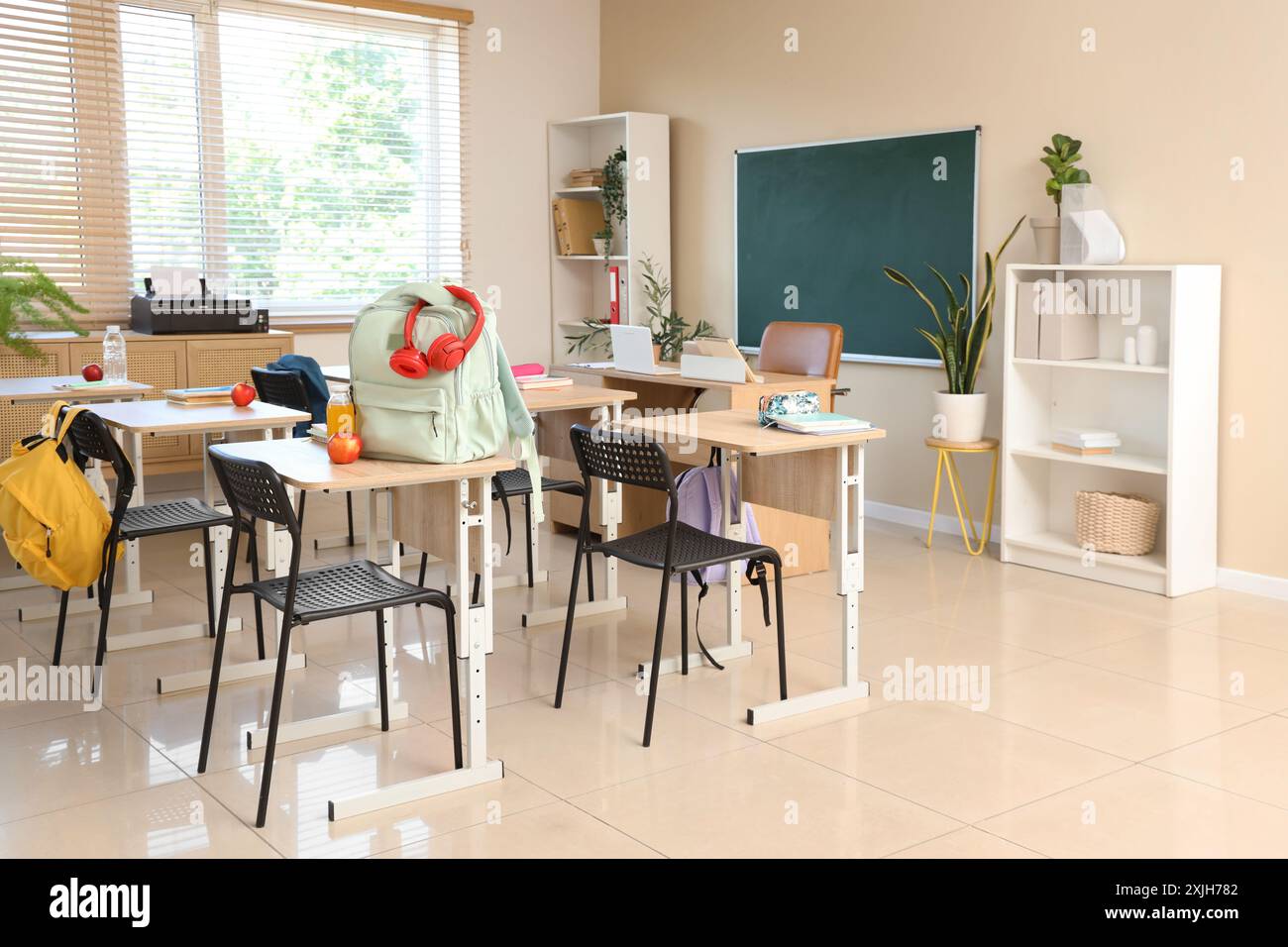Interior of empty classroom with chalkboard, shelf units and desks ...