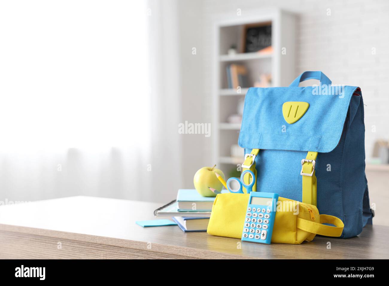 Apple, books, schoolbag and stationery on desk in classroom. Back to ...