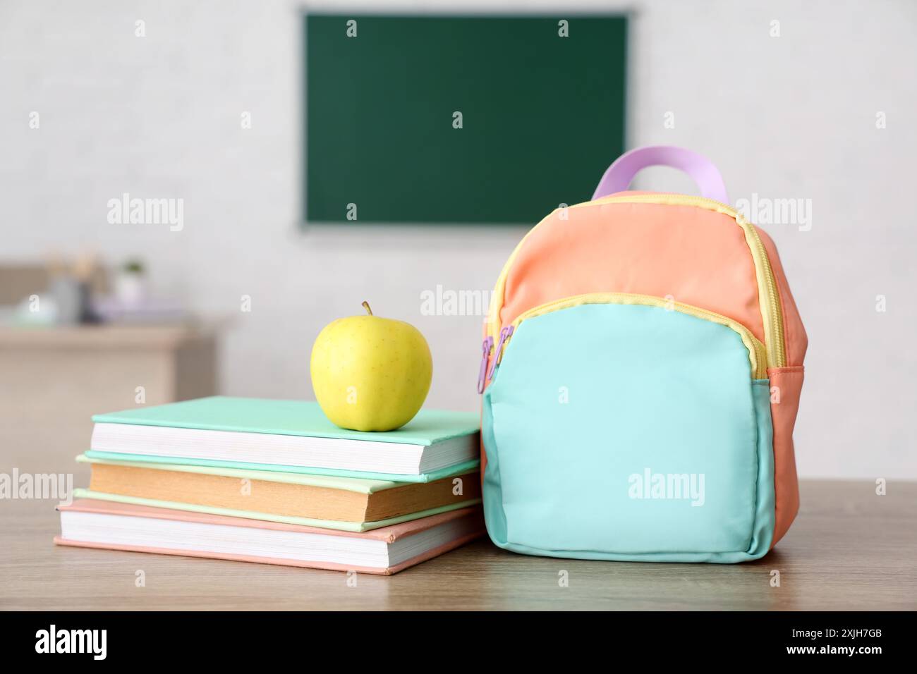 Apple, books and schoolbag on desk in classroom. Back to school concept ...