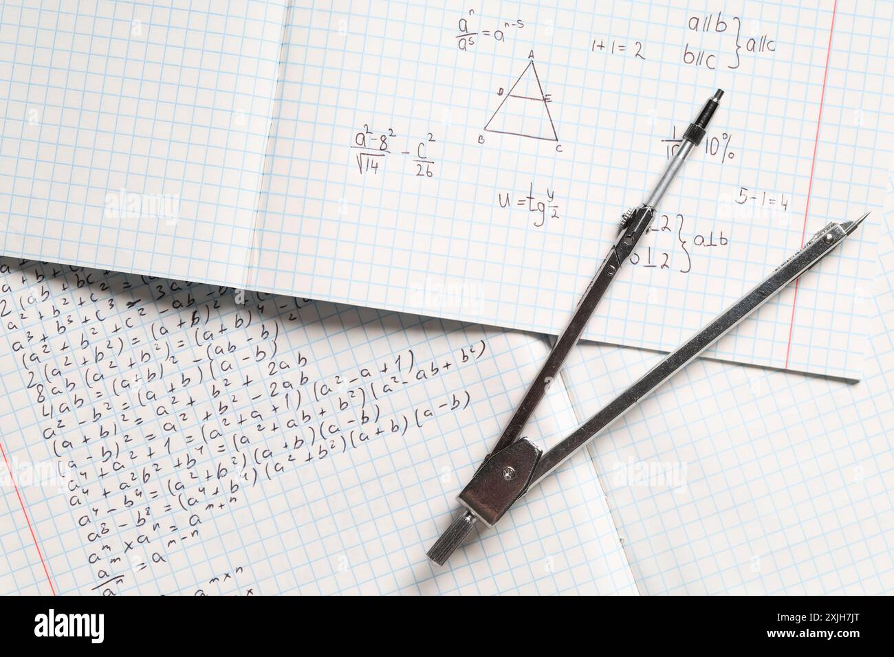 Copybooks with handwritten maths formulas and pair of compasses as ...