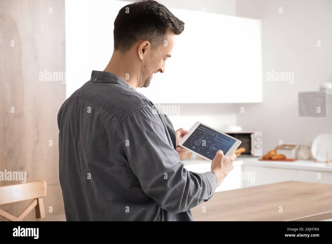 Young man using smart home security system control panel in kitchen ...