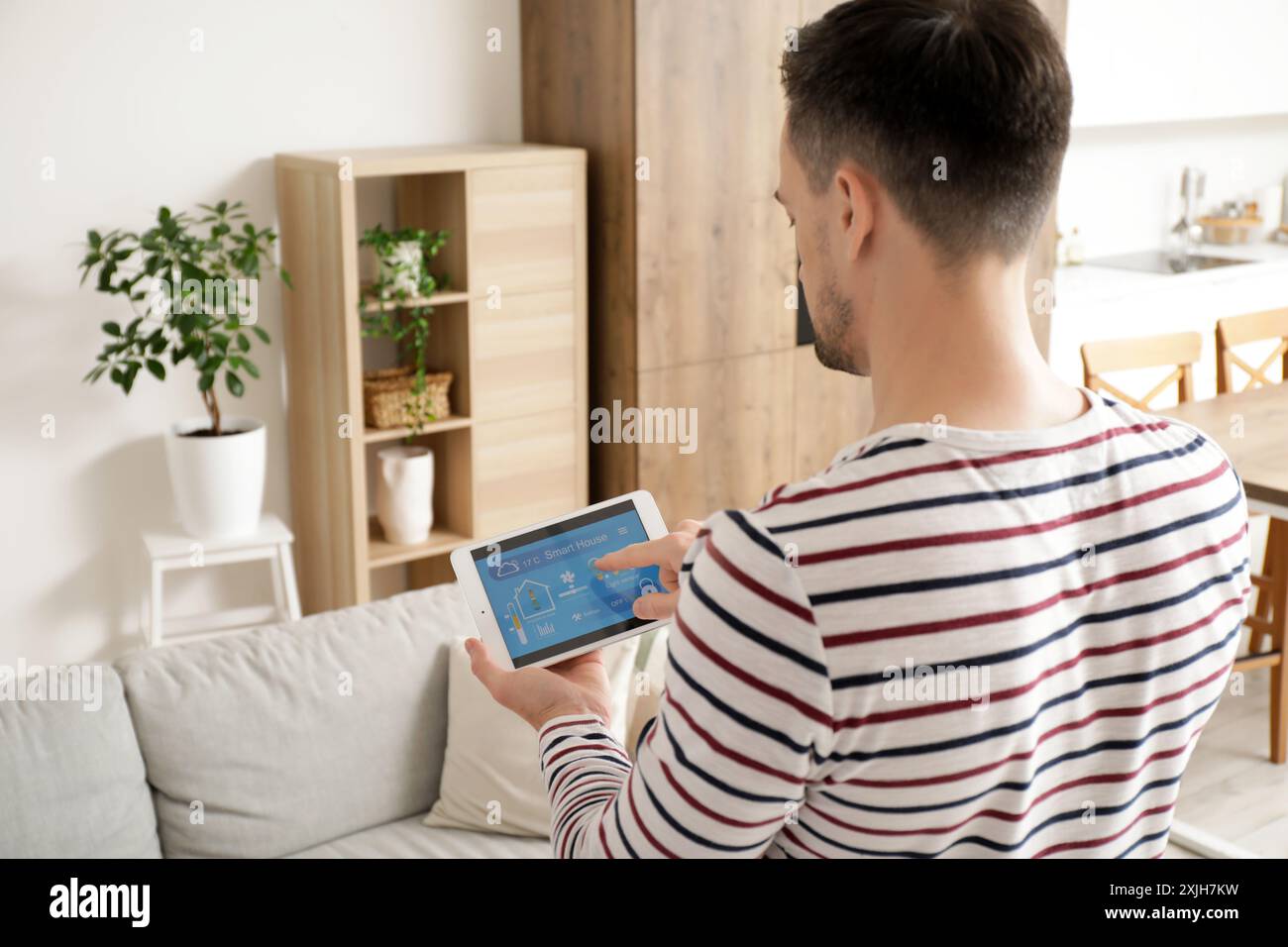 Young man using smart home security system control panel, back view ...