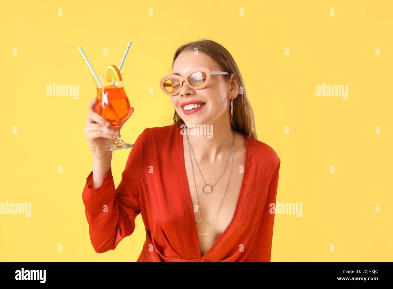 Beautiful young woman with aperol spritz cocktail on yellow background ...