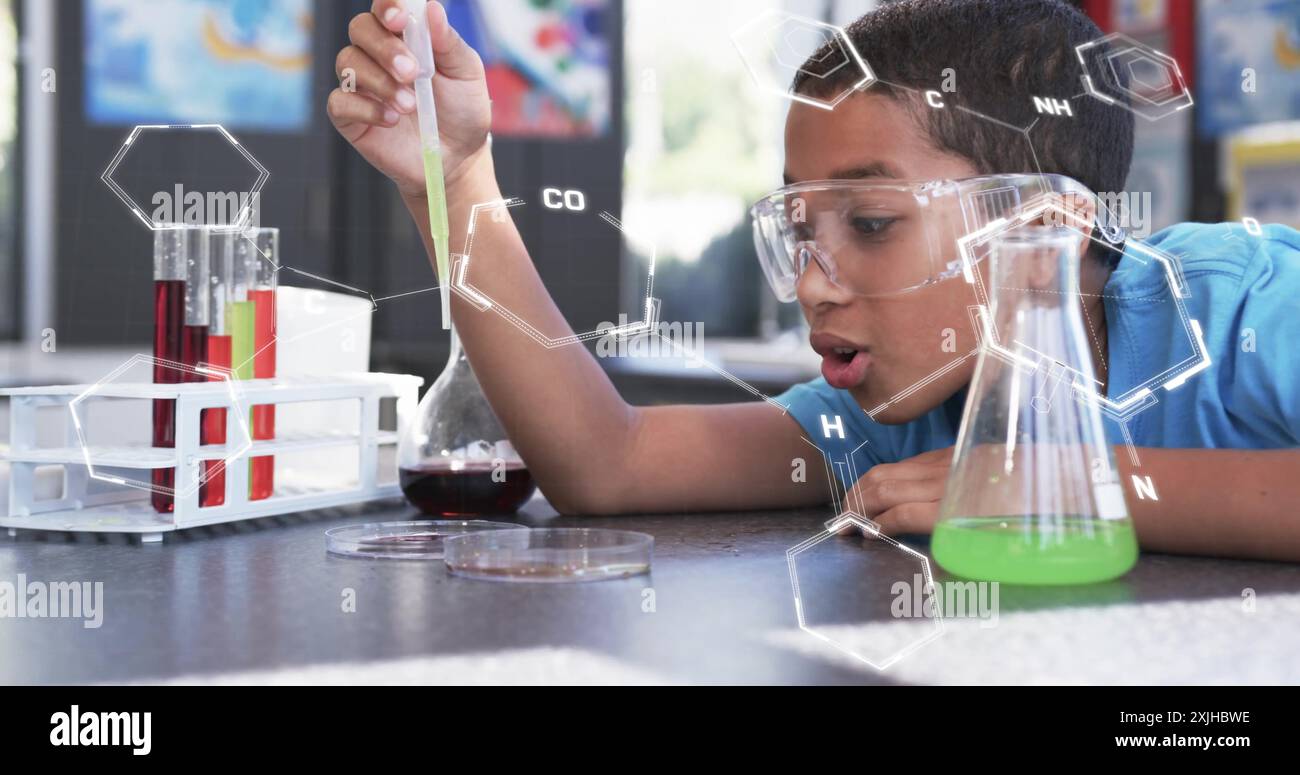 Conducting science experiment, child with safety goggles using pipette over chemical formulas ...