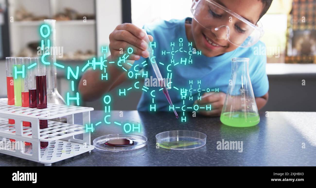 Conducting science experiment, child with safety goggles using pipette over chemical formulas ...