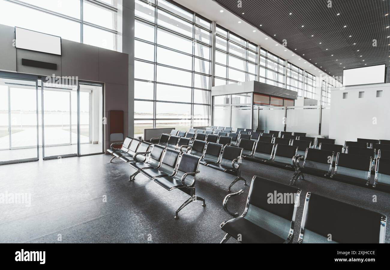 A modern airport waiting area with rows of empty black chairs facing ... A modern airport waiting area with rows of empty black chairs facing ...