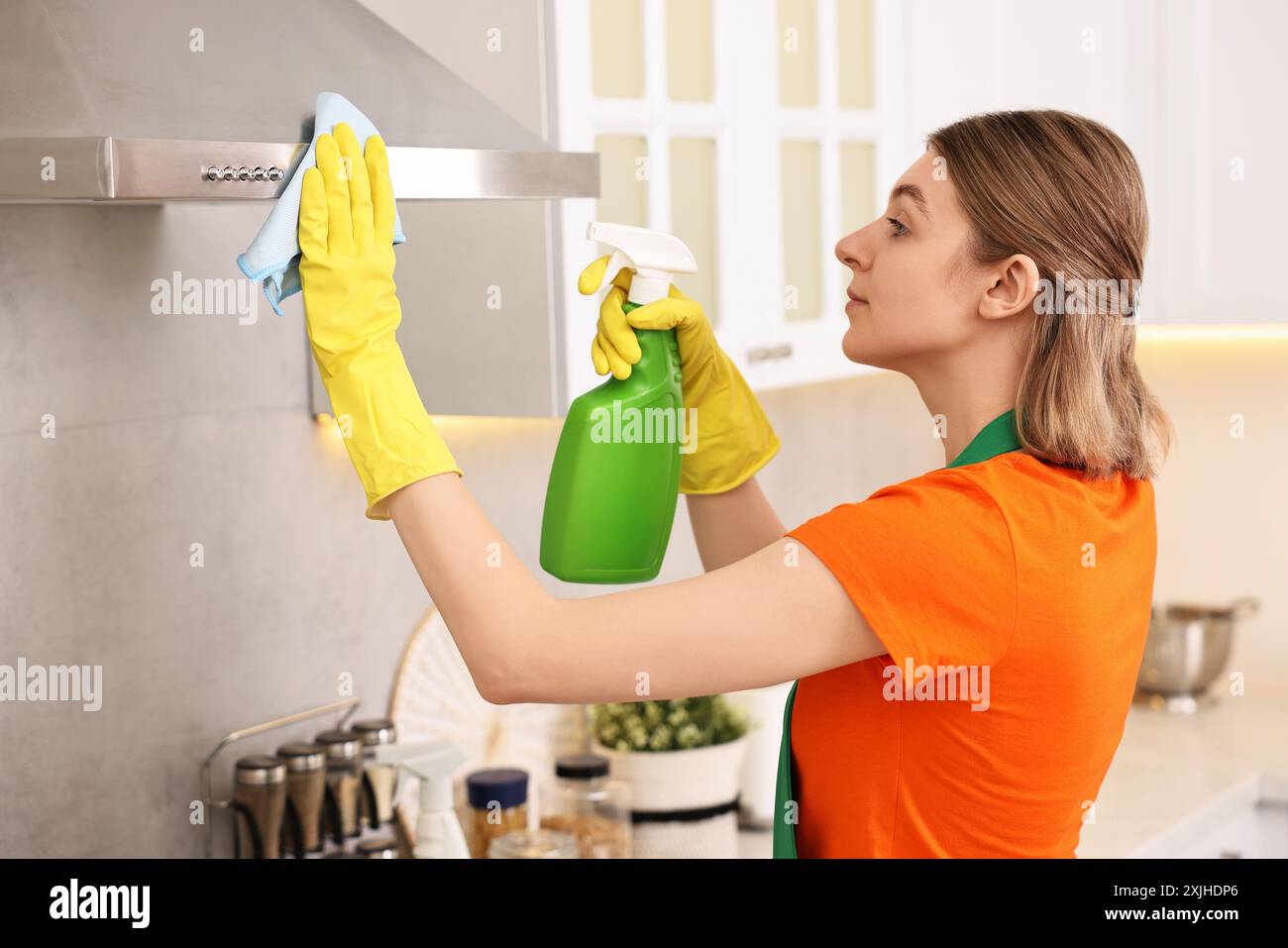 Professional janitor wearing uniform cleaning kitchen hood with rag and ...