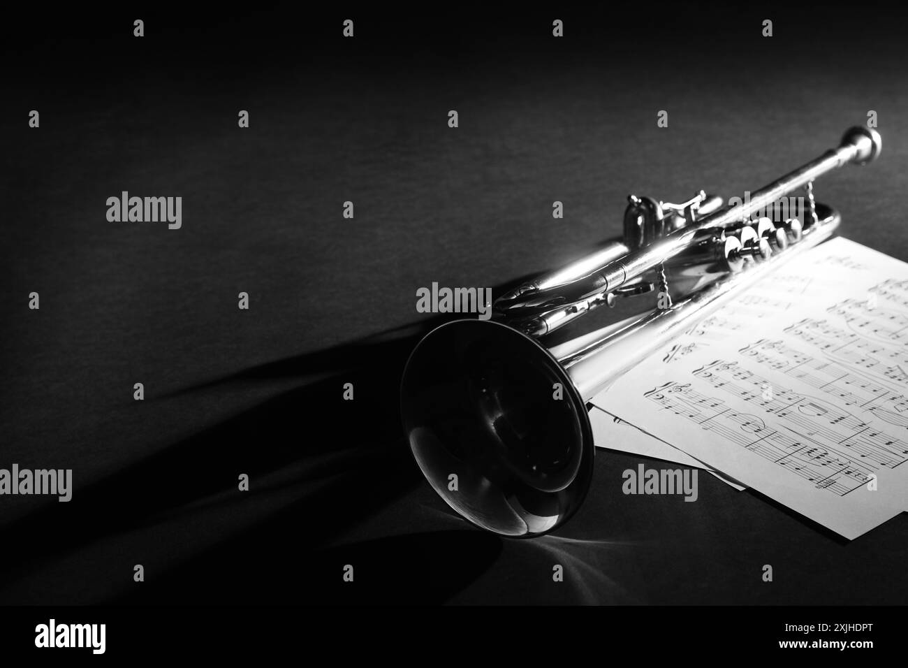 Shiny trumpet and music sheets on dark background, space for text. Wind ...