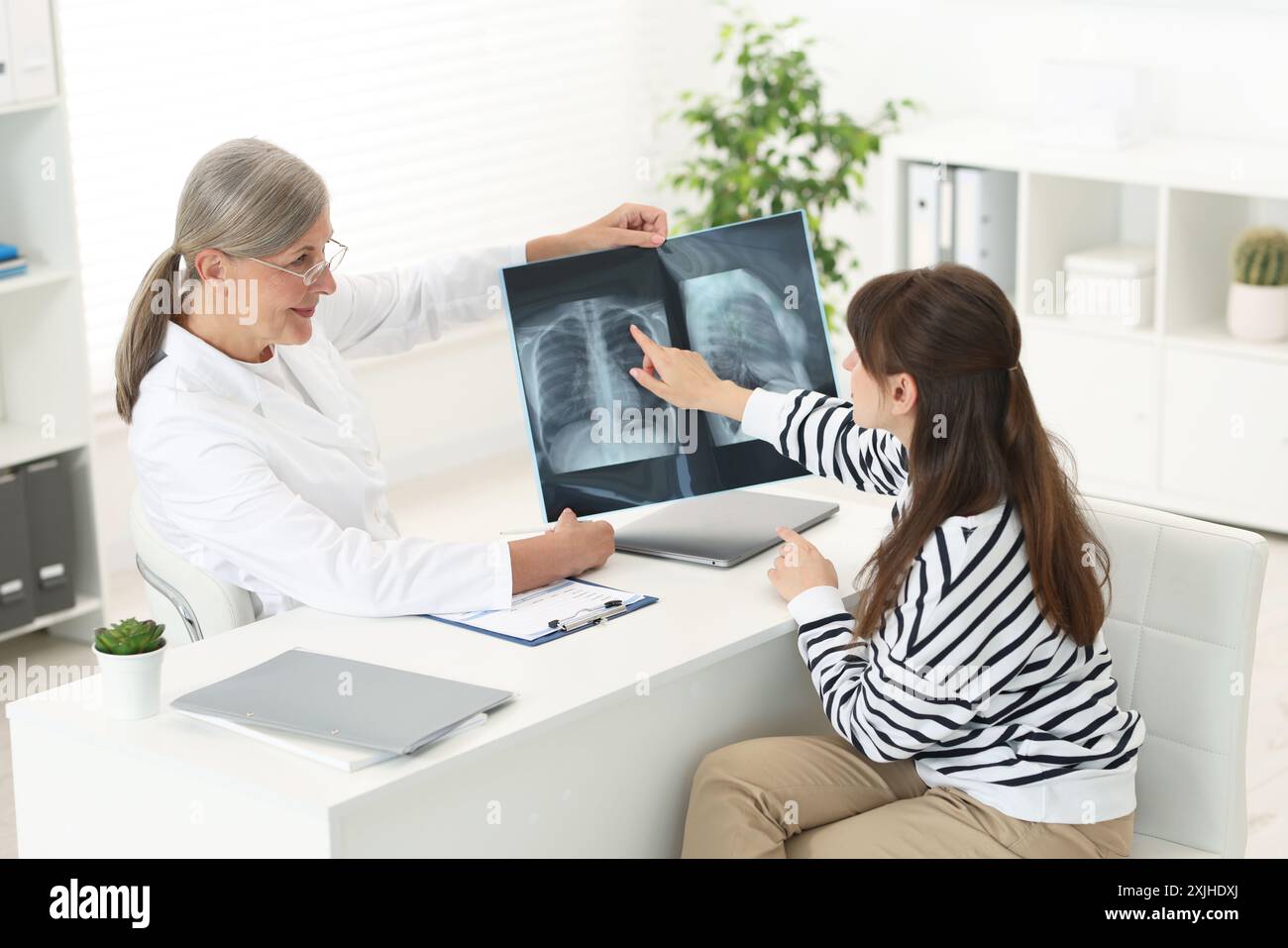 Lung disease. Doctor showing chest x-ray to her patient at table in ...