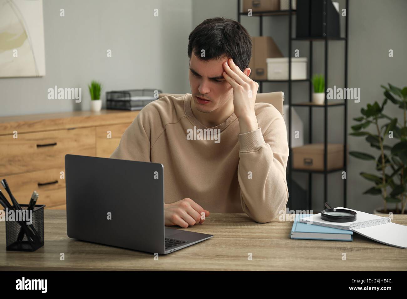 Embarrassed man at wooden table with laptop in office Stock Photo - Alamy