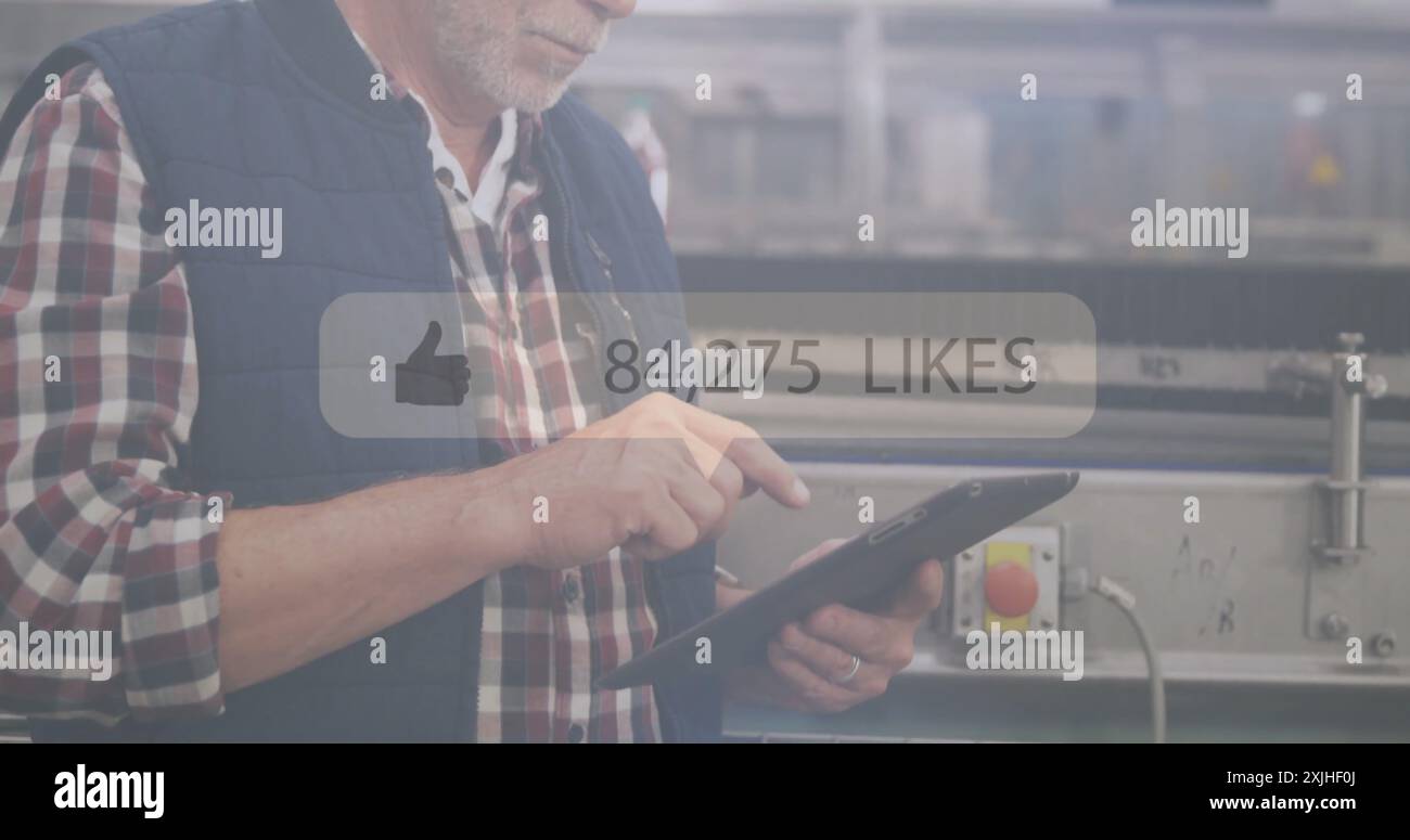 Using tablet, man in industrial setting with social media likes image overlay. Technology ...