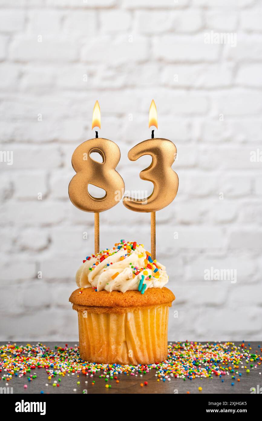 Golden birthday candle number 83 with cupcake - White block wall ...
