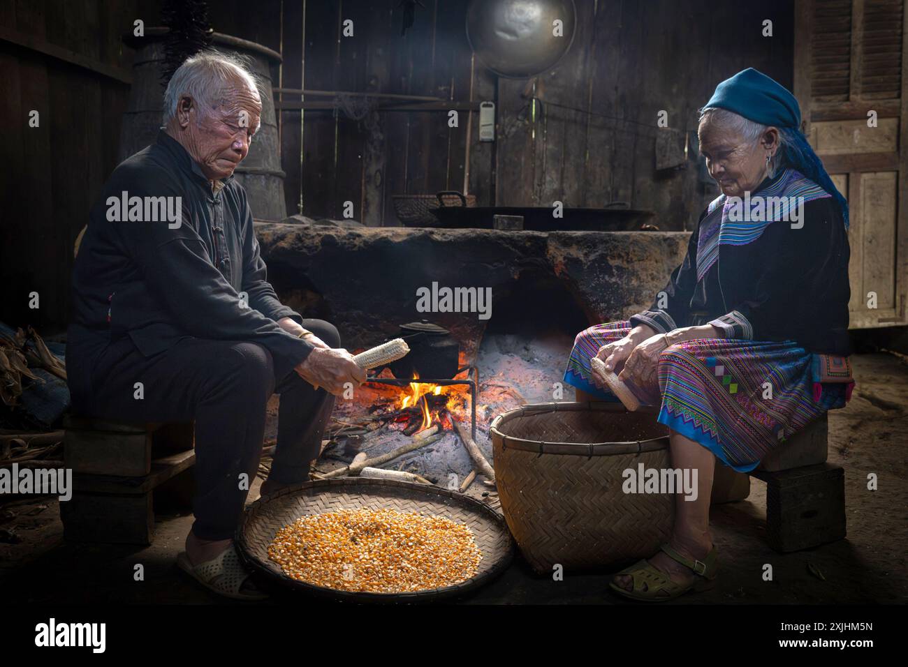 Flower Hmong man and woman shelling corn in their kitchen in Bac Ha ...