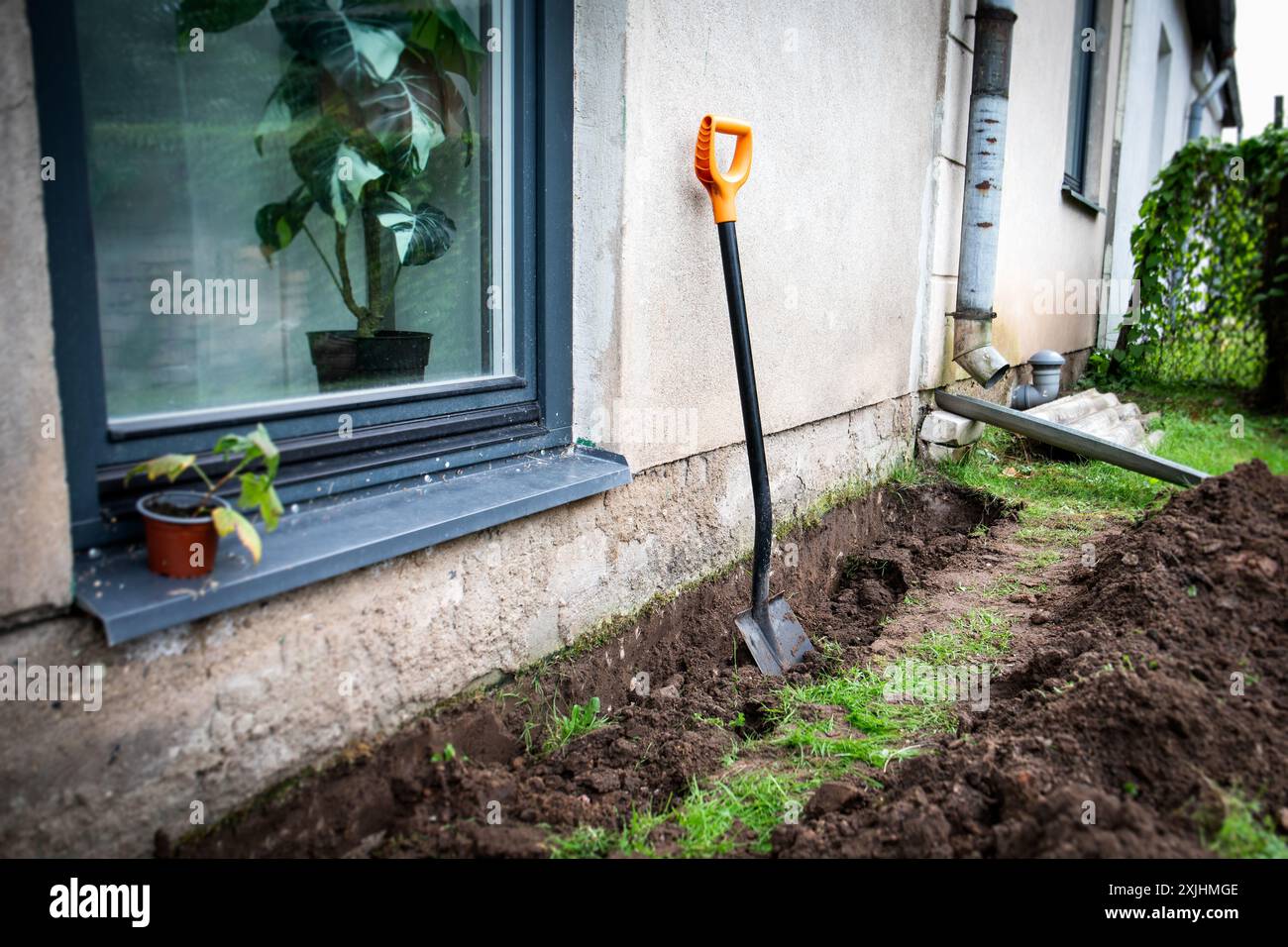 A trench at the foundation of the house and a shovel. Preparing for ...