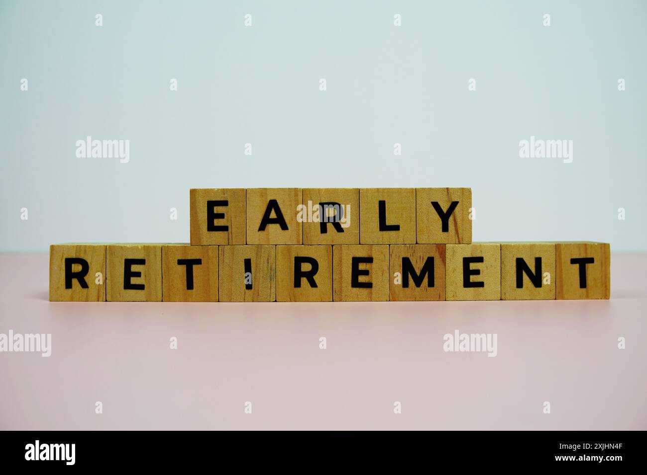 wooden blocks alphabet letters EARLY RETIREMENT on pink background ...